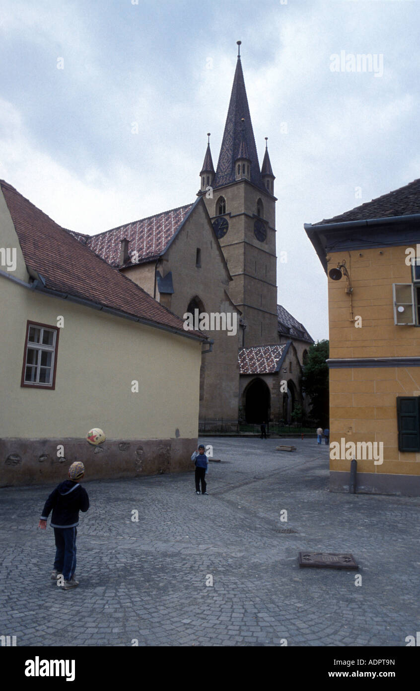 Sibiu, Romania. 2 children playing with a ball on maze of old streets ...