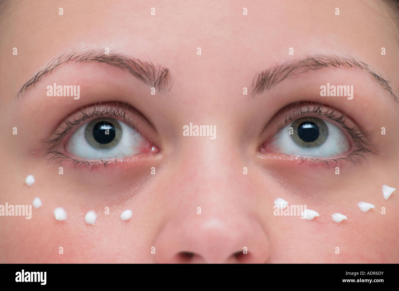 Young woman with moisturizer under eyes close up Stock Photo - Alamy