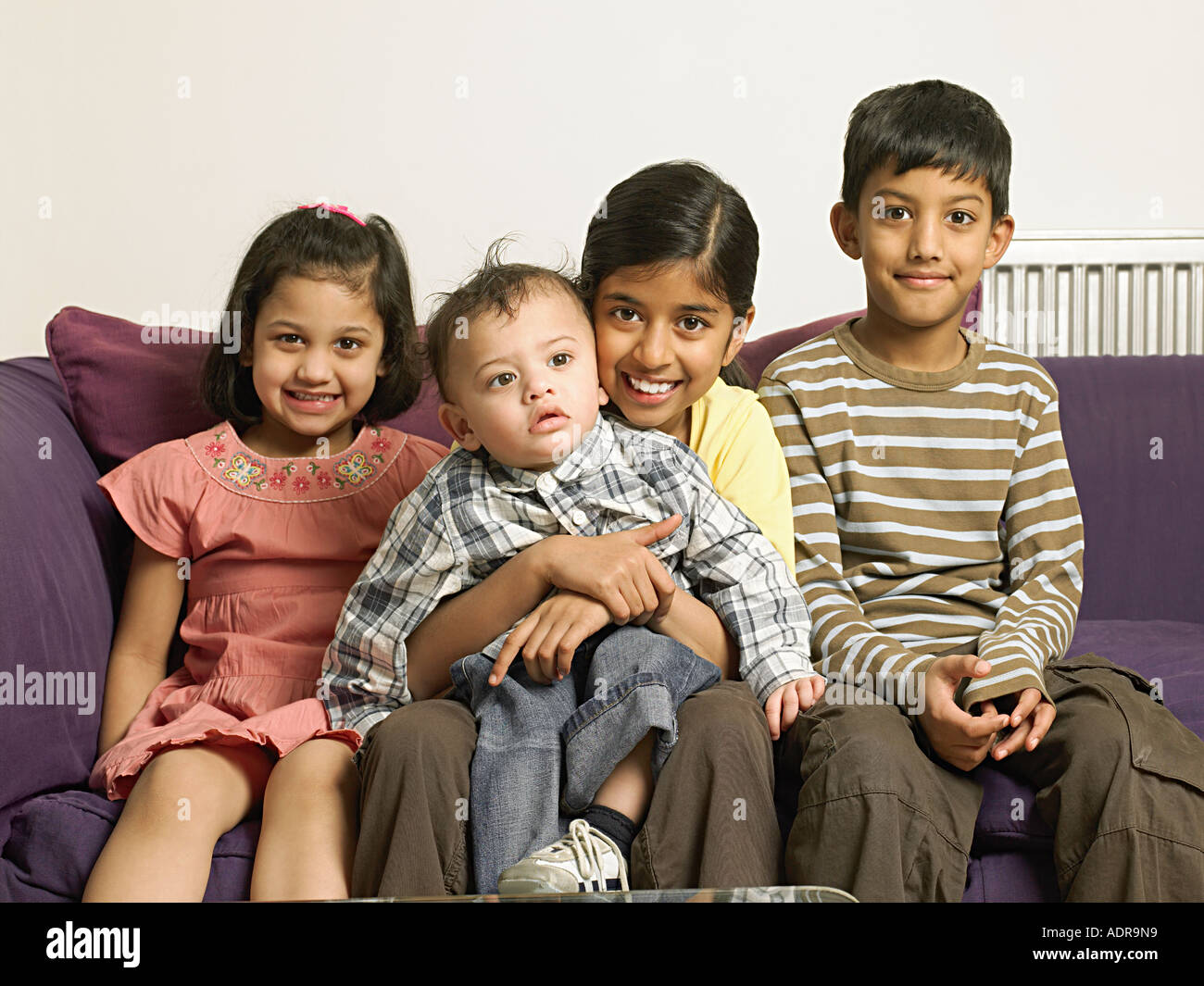 Four children sitting on sofa Stock Photo - Alamy