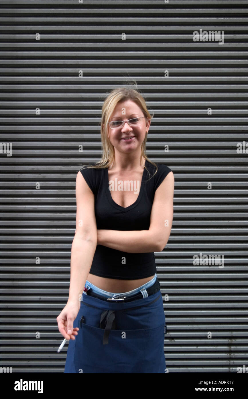 Waitress having cigarette break in front of shutters. Southwark, London ...