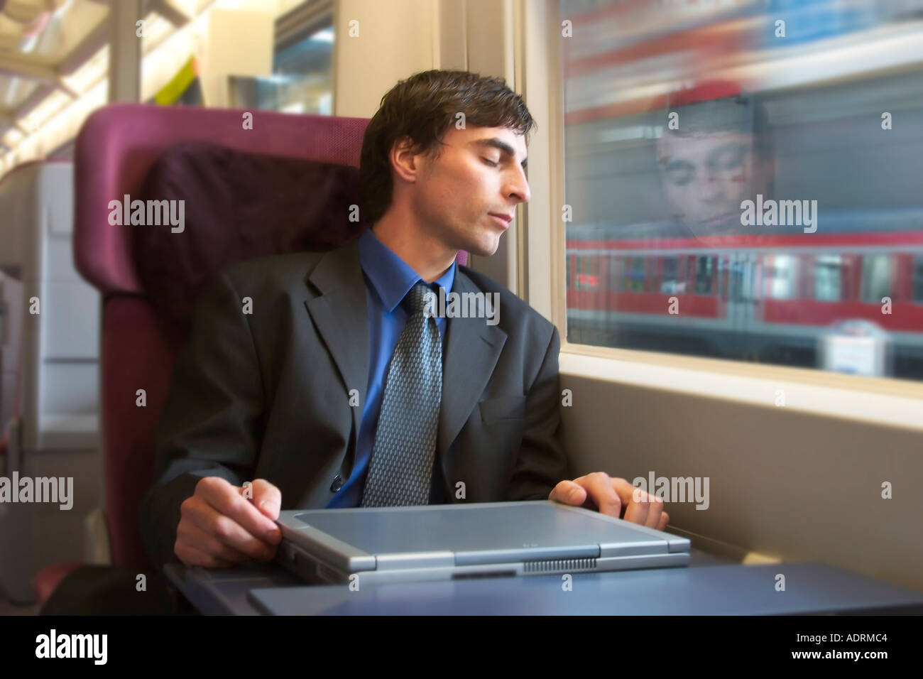 Businessman with laptop sleeping in a train Stock Photo - Alamy