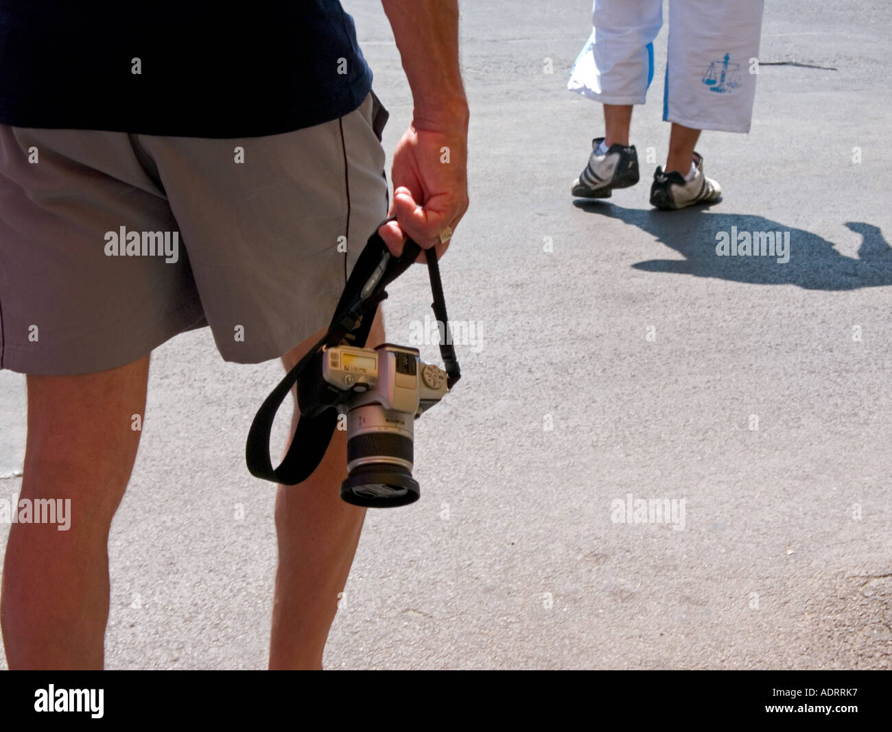 a cropped shot of man's legs and hand carrying a camera Stock Photo - Alamy