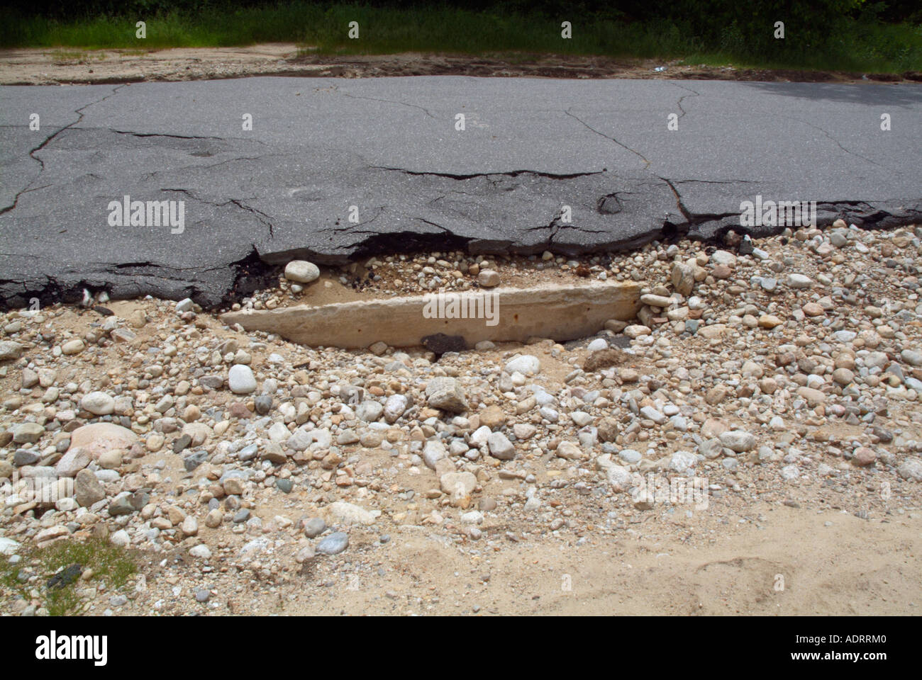 A section of washed out road from water over flowing a small pond Stock ...