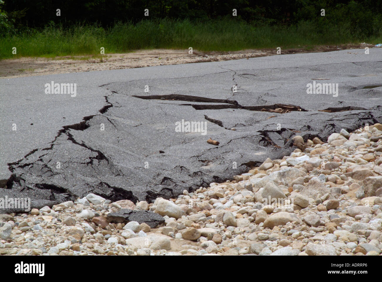 A section of washed out road from water over flowing a small pond Stock ...
