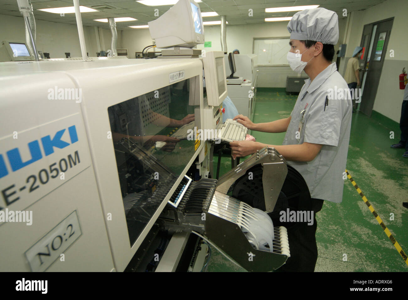 Chinese High Tech Factory worker at machine for putting components on ...
