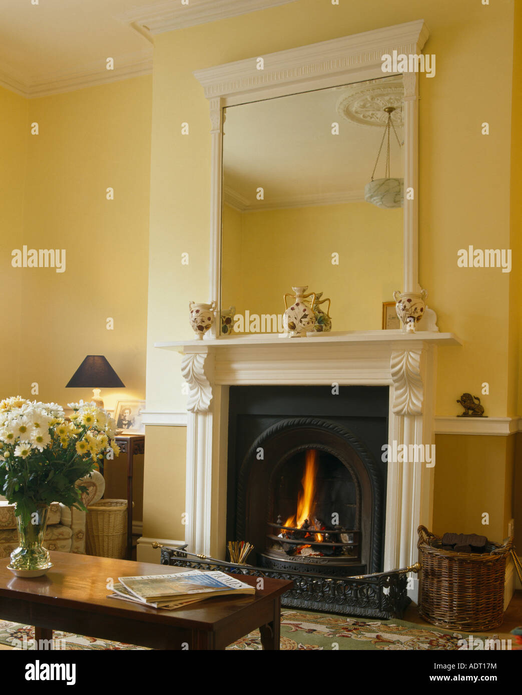 White mirror above white fireplace in pastel yellow livingroom Stock ...