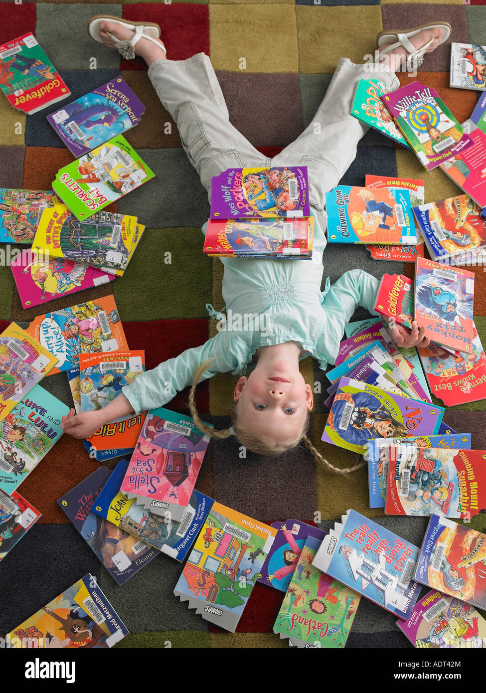 Girl lying on library floor with books scattered around, view from ...