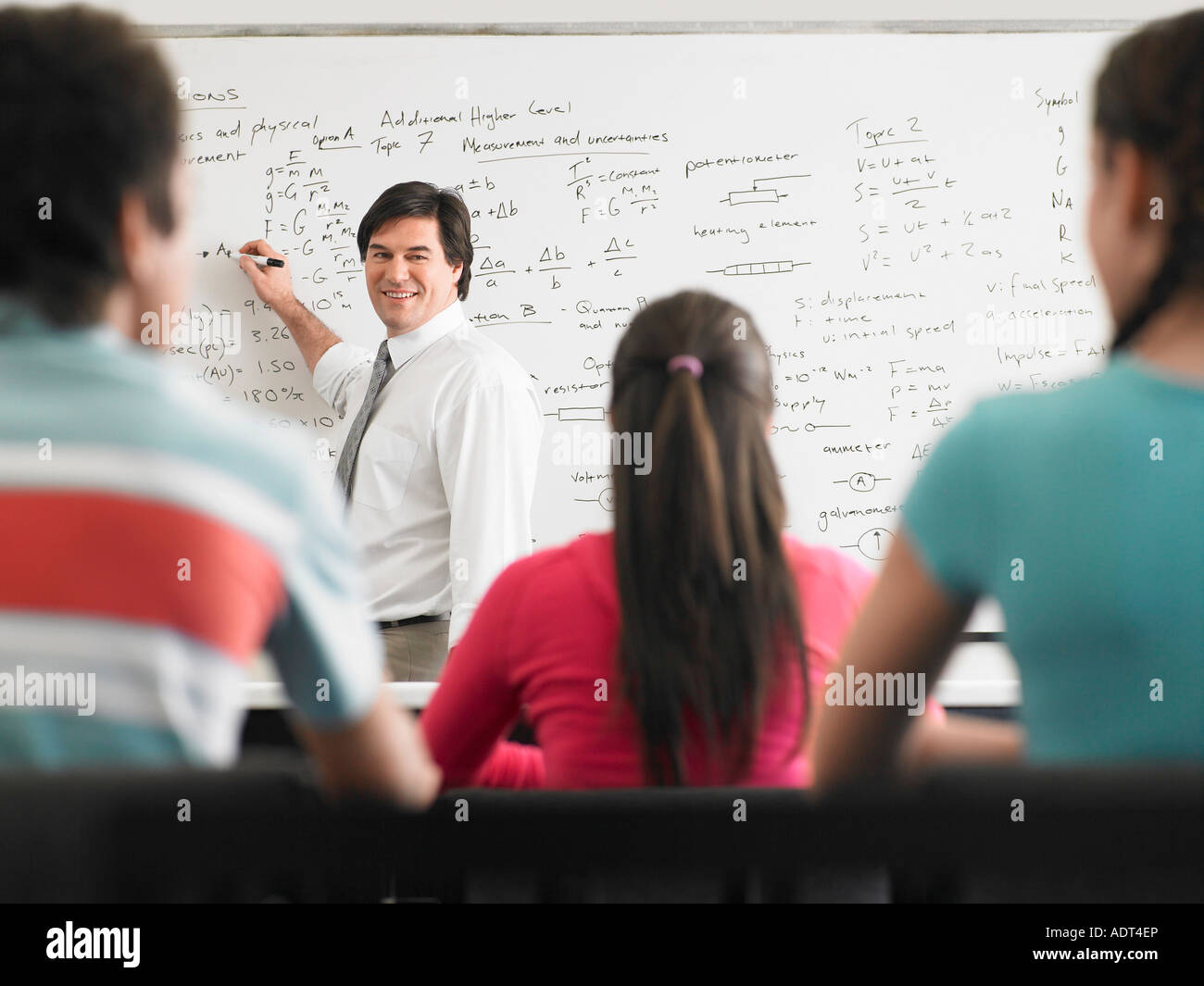 Teacher writing on whiteboard in classroom Stock Photo - Alamy