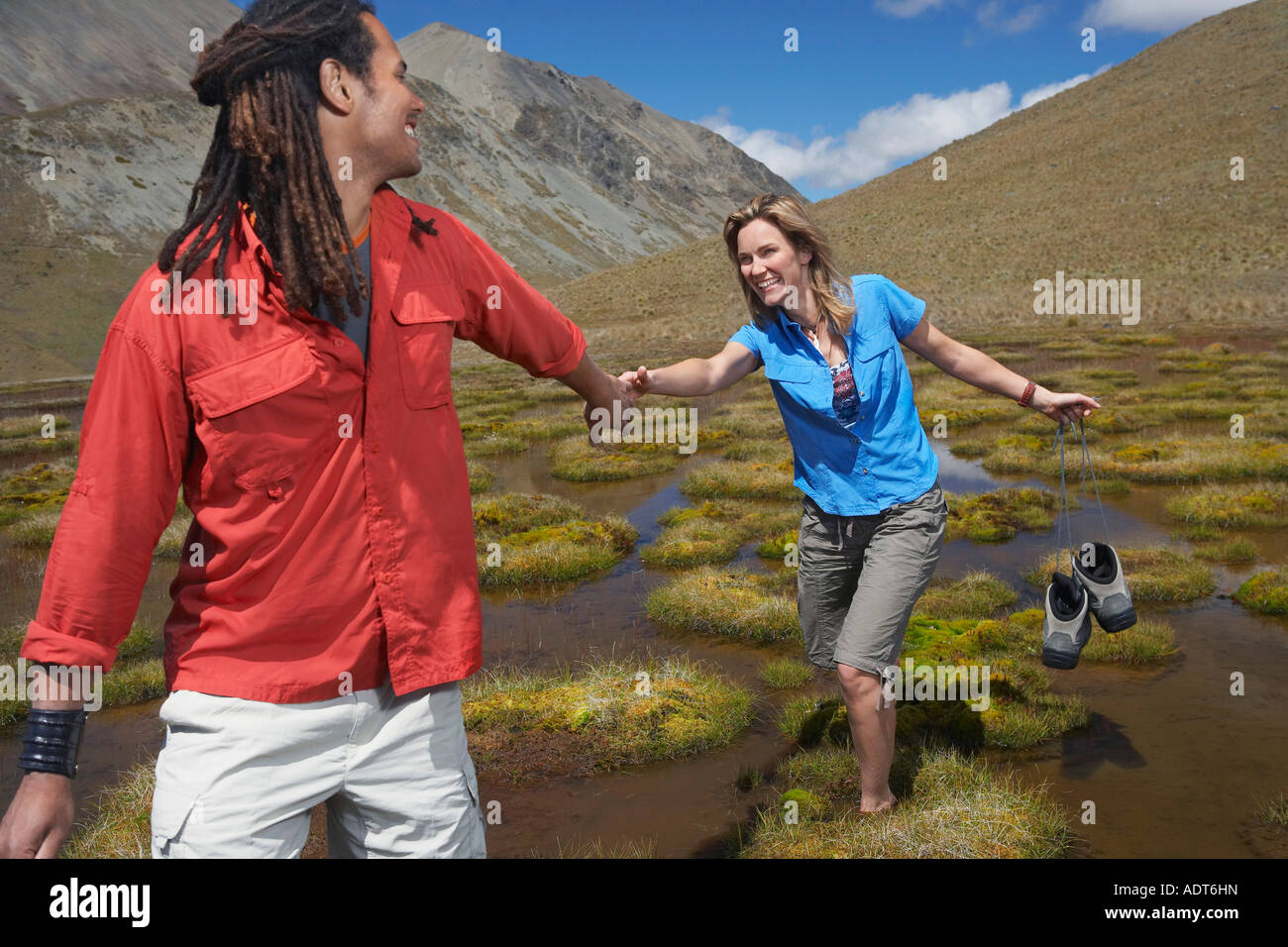Man helping woman wade through pond while she is carrying shoes Stock ...