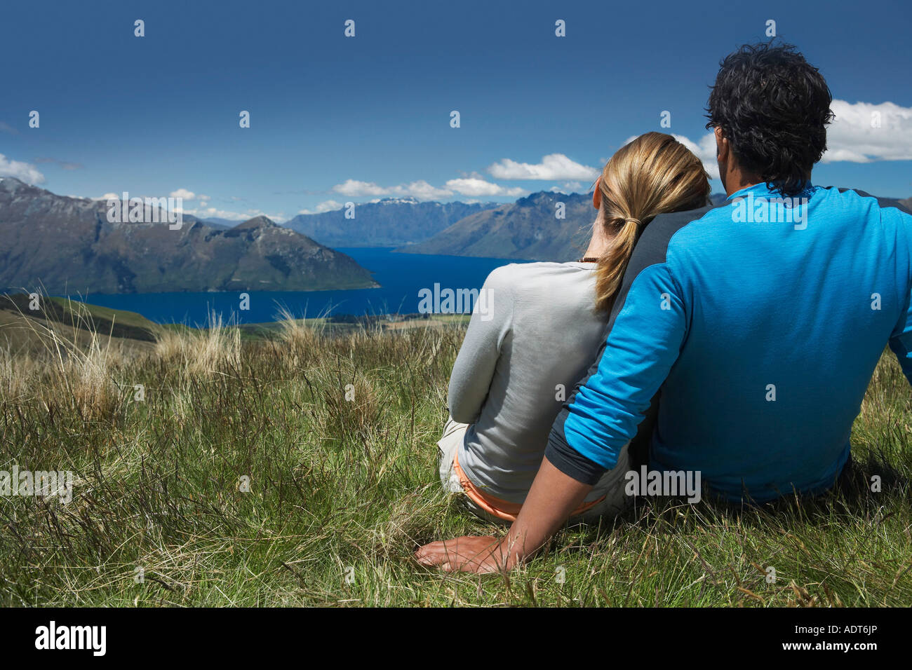 Couple cuddling looking over lake and hills, back view Stock Photo - Alamy