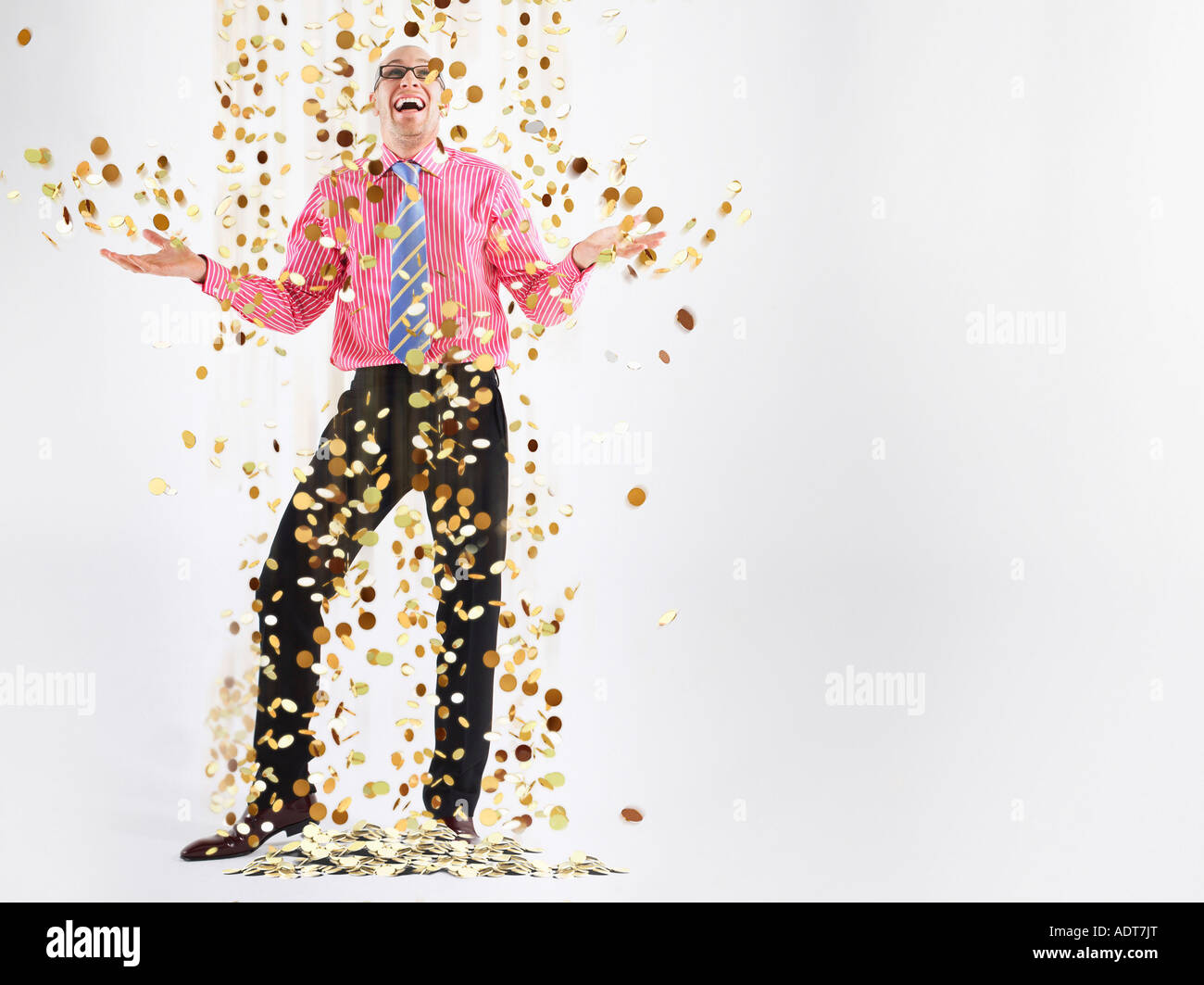 Man in glasses laughing with gold coins falling to floor Stock Photo ...
