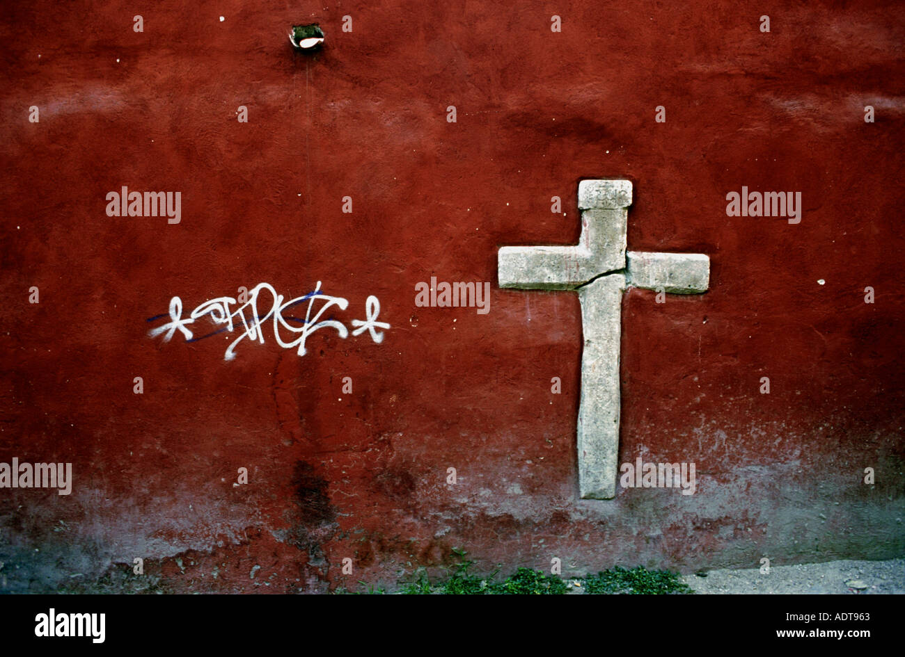 A traditional Christian cross and some modern graffiti adorn a wall in ...