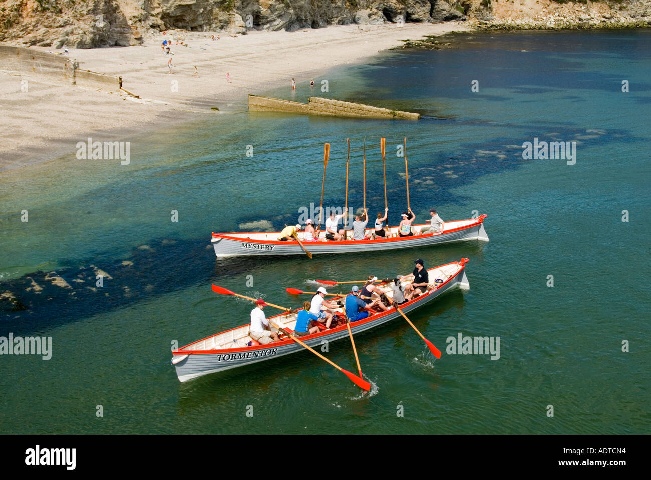 Winners hold oars aloft two mixed teams of long pilot gig row boats ...