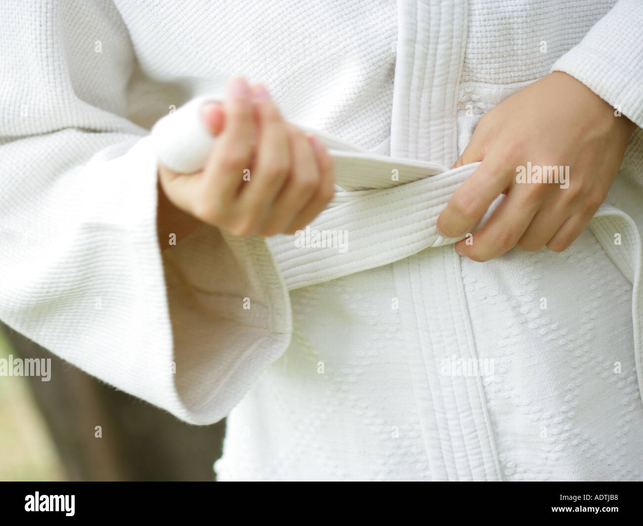 Mid section view of a young woman tying her belt Stock Photo - Alamy