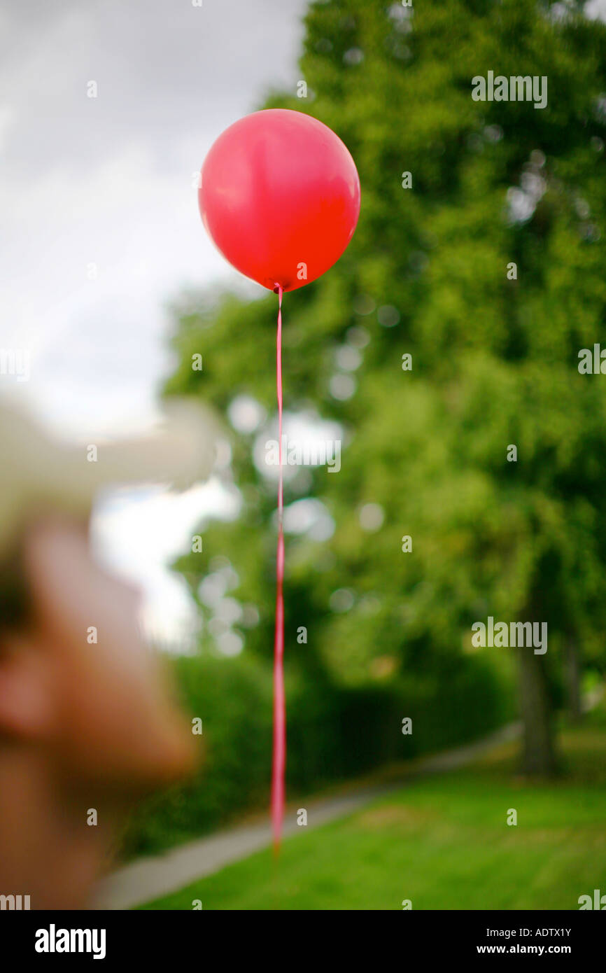 Single red balloon drifts up to the sky with man looking away from ...