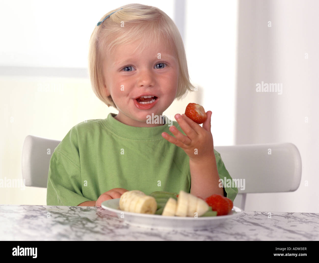 Little girl eating fruit Stock Photo - Alamy