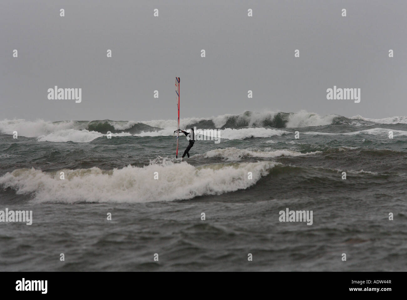 windsurfer braves the big waves on a windy bad weather summers day at ...