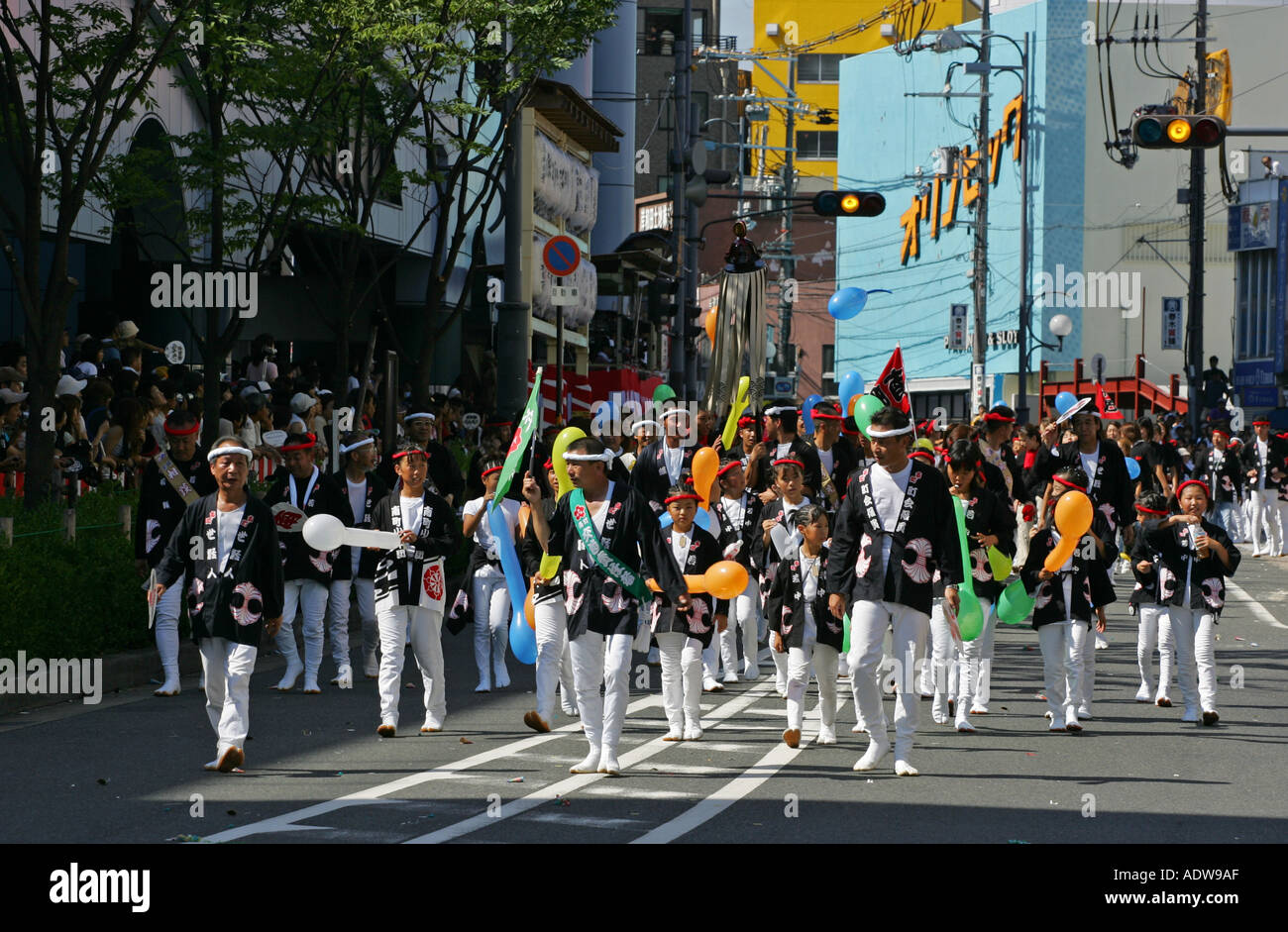 Children in festival costumes carrying brightly coloured baloons parade ...