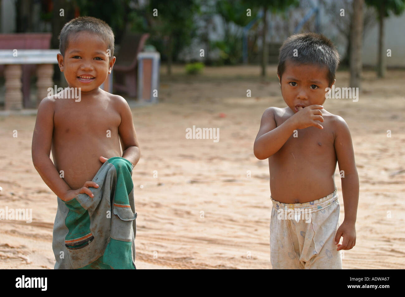 Two young Cambodian village boys friends playing in a muddy street in ...