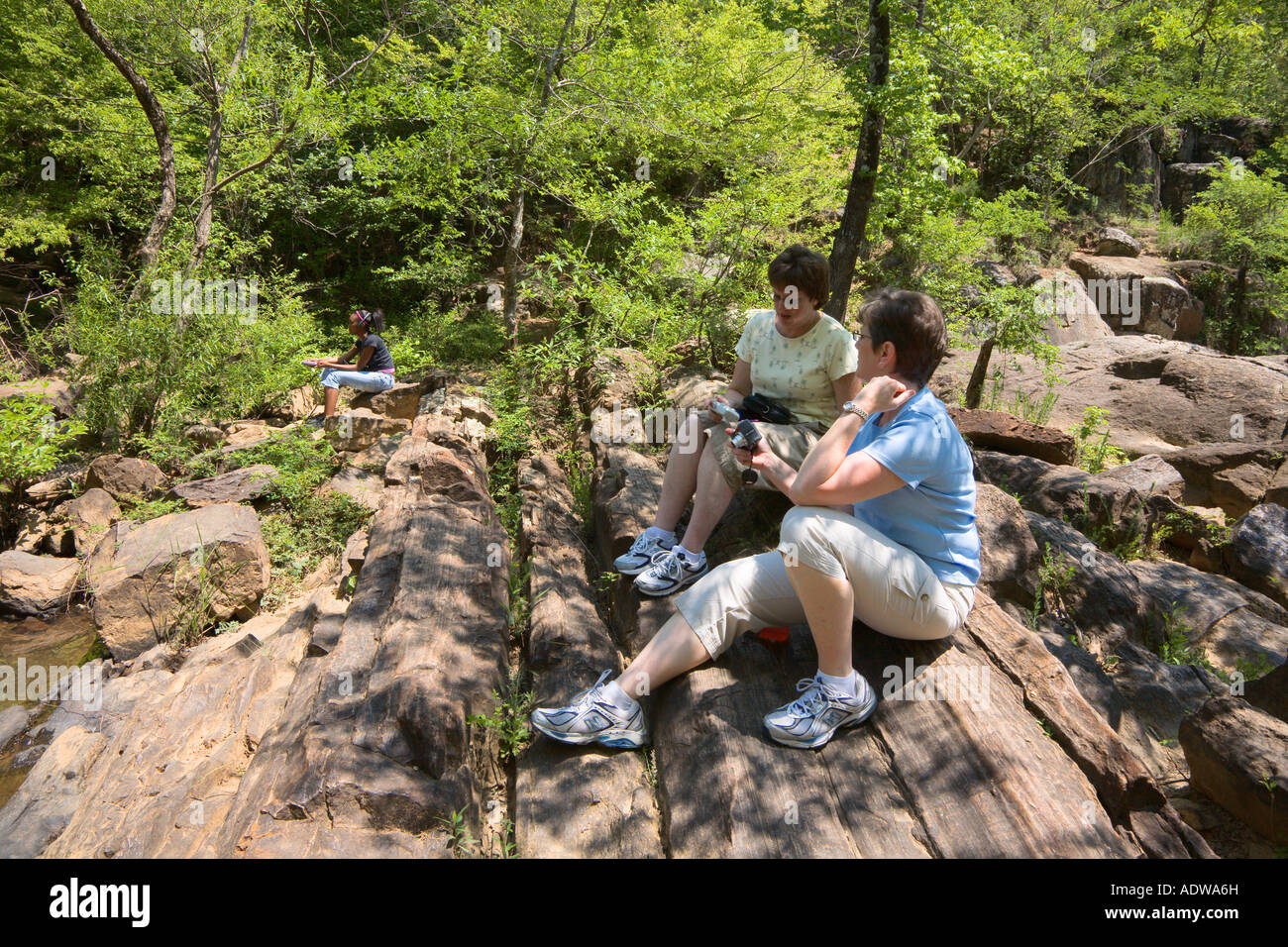 Two women sitting on rocks under a tree at Chewacla State Park in ...