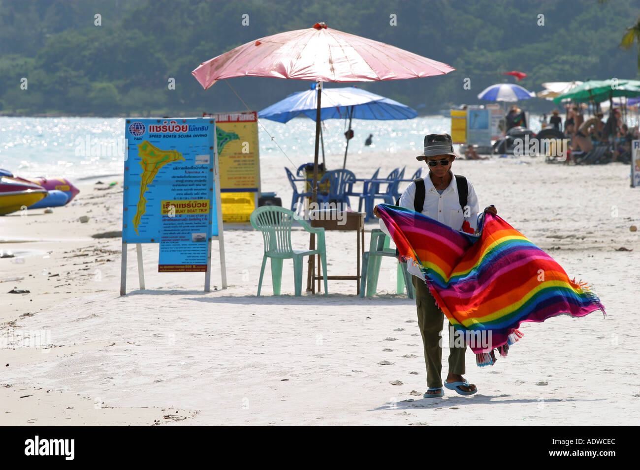 A Thai hawker walks up and down the golden beachfront selling his silk ...