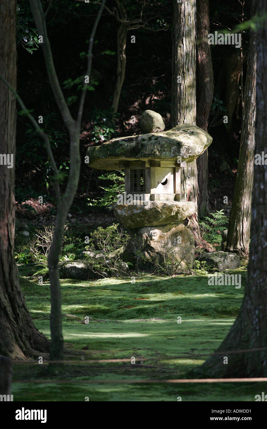 A traditional Japanese stone garden lantern stands on the lush green ...