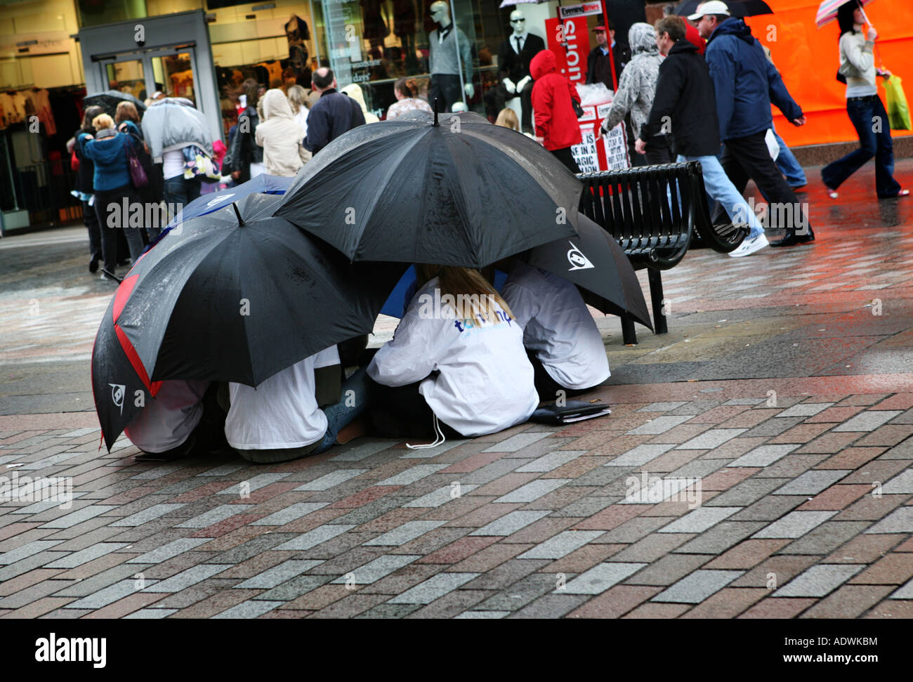A group of young people hiding underneath black umbrellas on Argyle ...