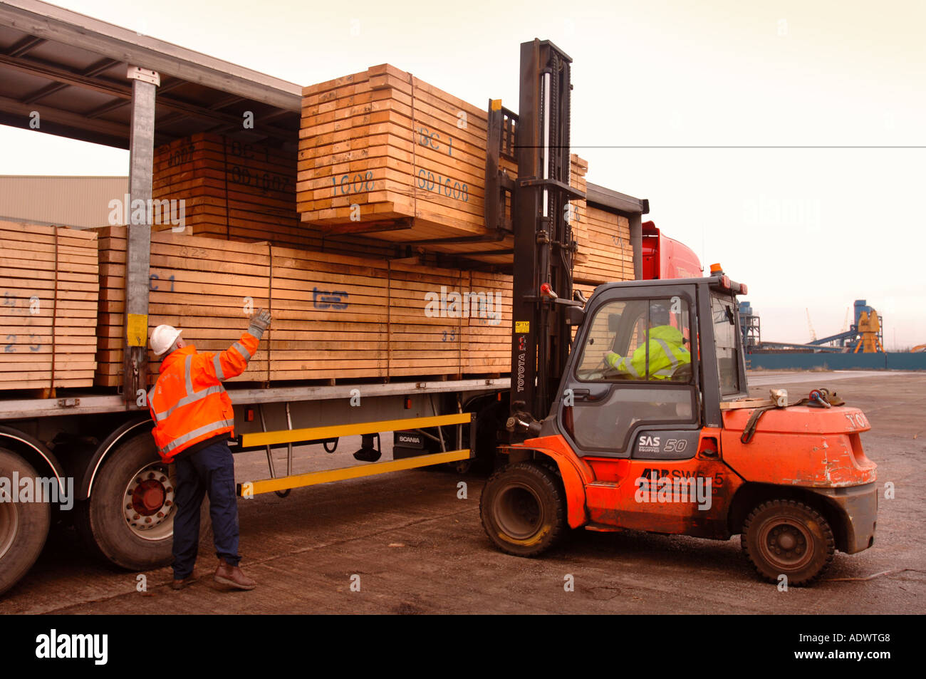 A FORK LIFT TRUCK LIFTS TIMBER ONTO AN ARTICULATED LORRY ON THE ...
