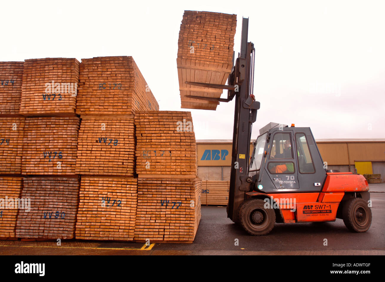 A FORK LIFT TRUCK LIFTS TIMBER ON THE DOCKSIDE AT A PORT IN NEWPORT ...