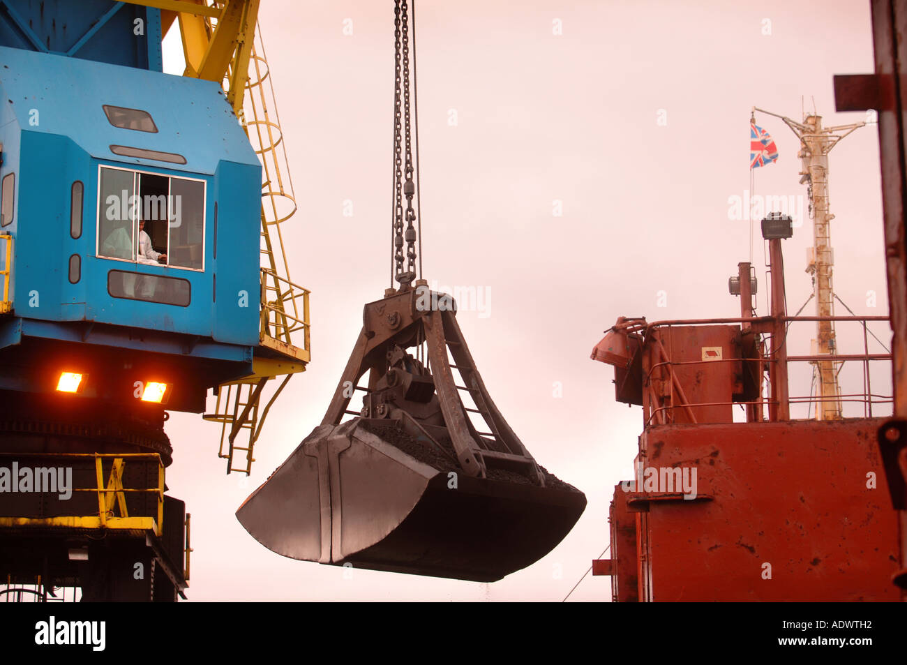 A CRANE UNLOADING COAL FROM A CONTAINER SHIP ON THE DOCKSIDE AT A PORT ...