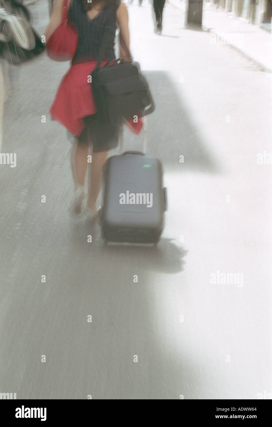 woman pulling trolley case on road blurred Stock Photo - Alamy