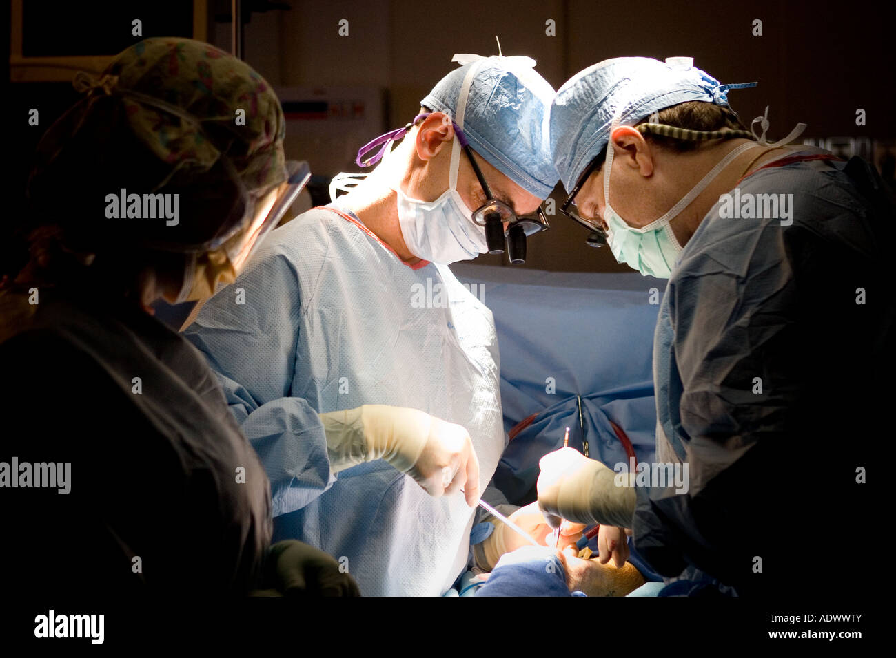 2 two vascular surgeons performing an operation on a patient's arm ...