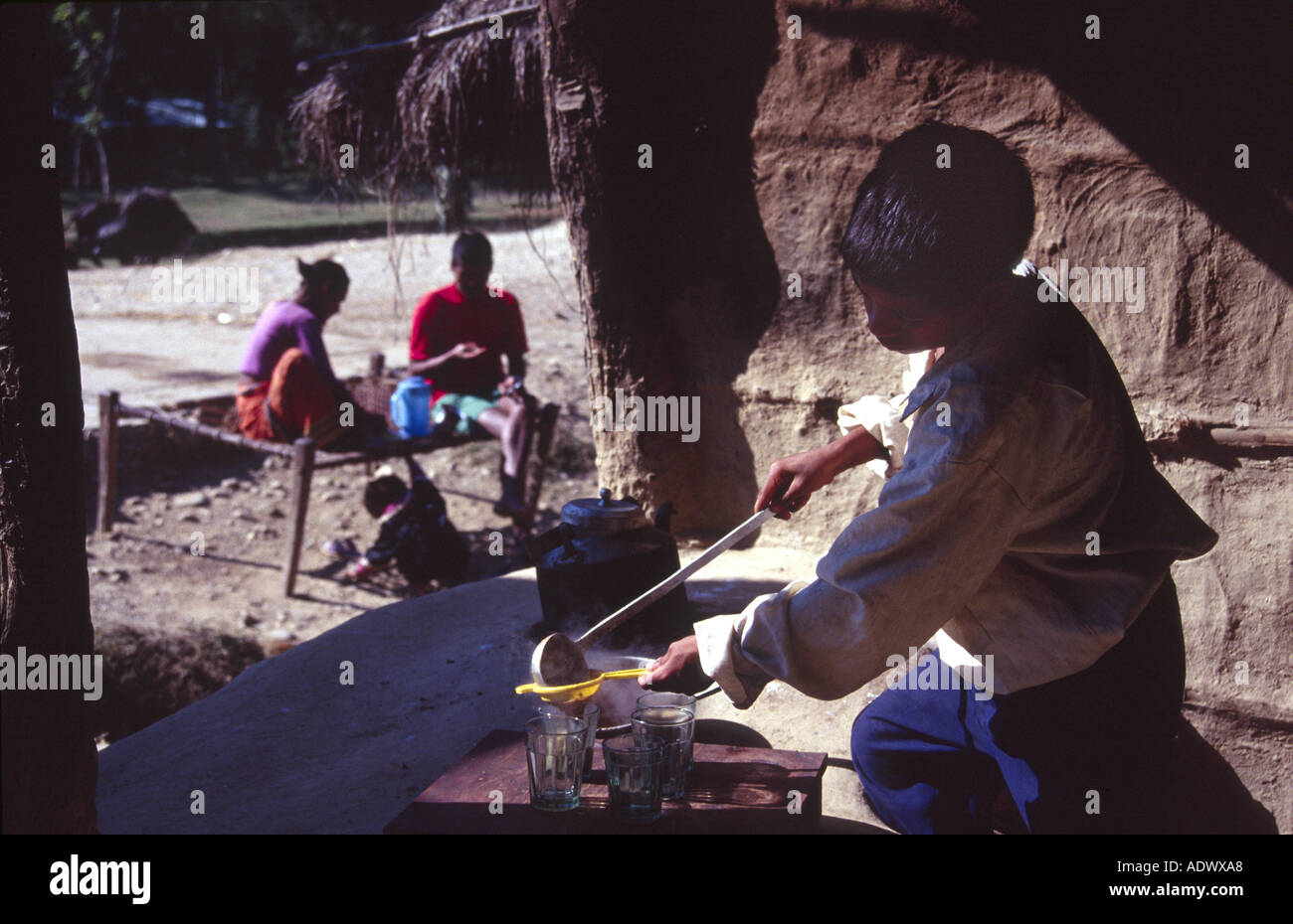 Boy making tea or chai as his parents look on, Nepal Stock Photo - Alamy