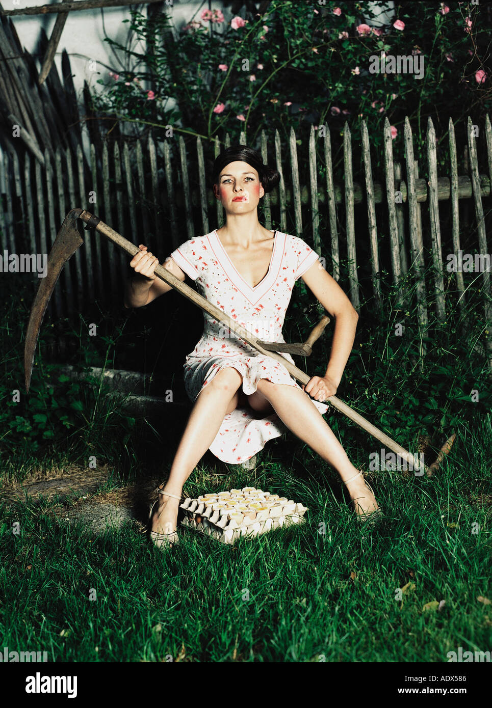 Woman sitting in garden, holding scythe Stock Photo - Alamy