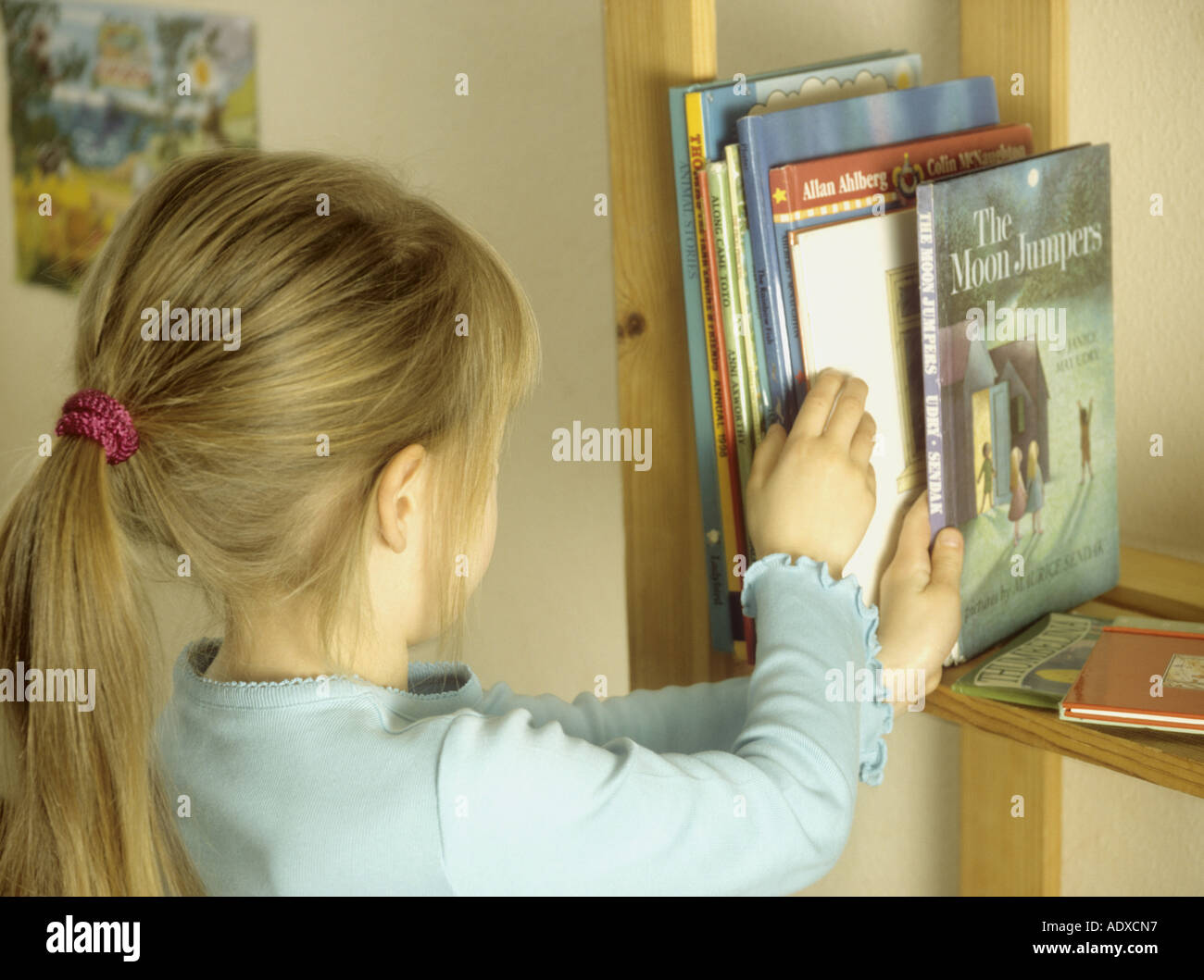 Child taking a book from a bookcase Stock Photo - Alamy