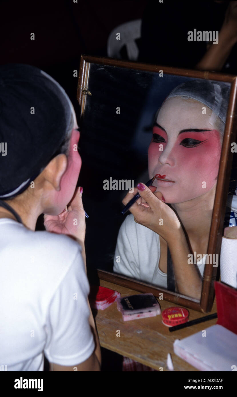 A Chinese opera singer making up her face in preparation for her ...
