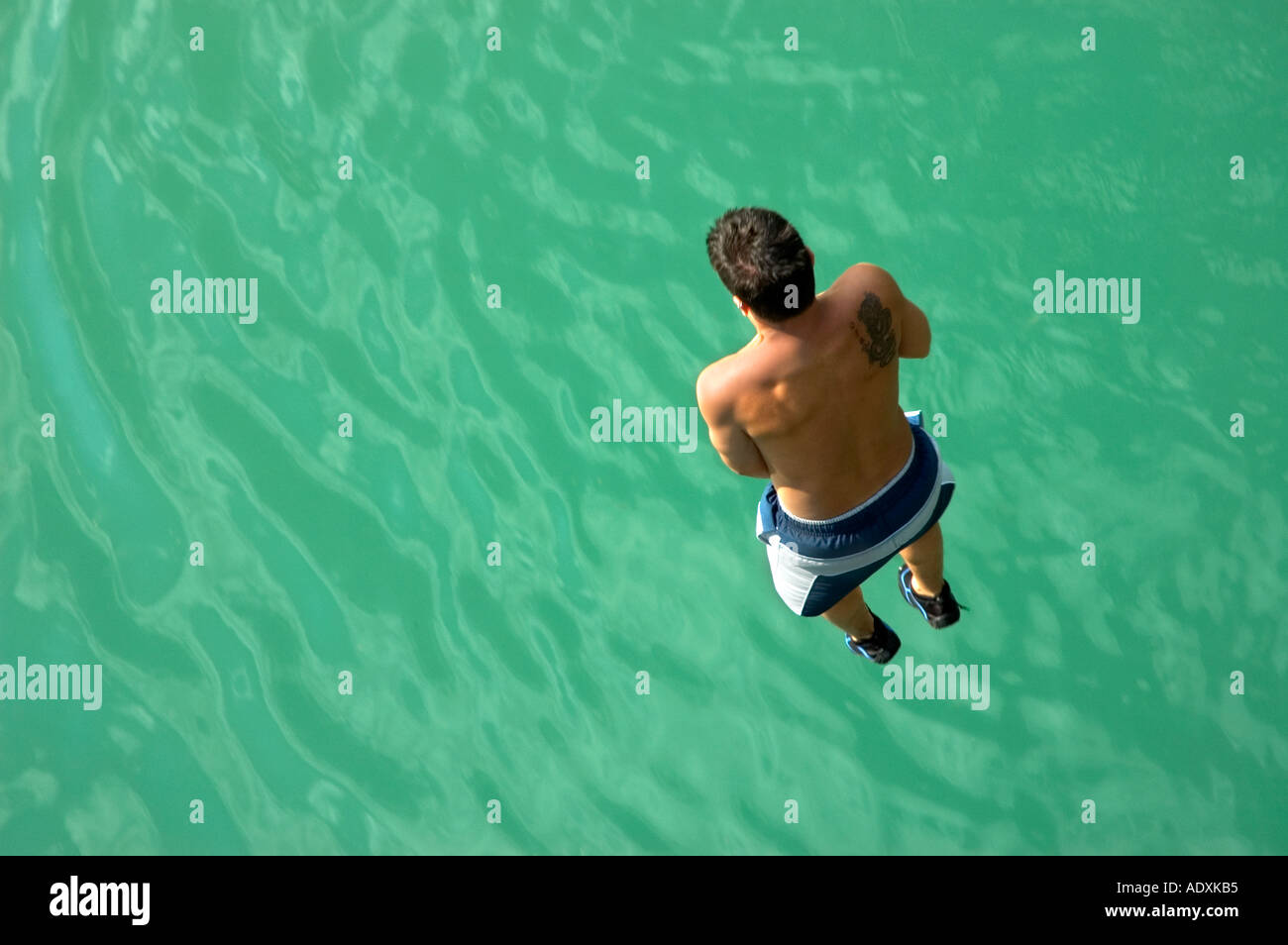 young people jump into green water from a bridge - meduno - region of ...