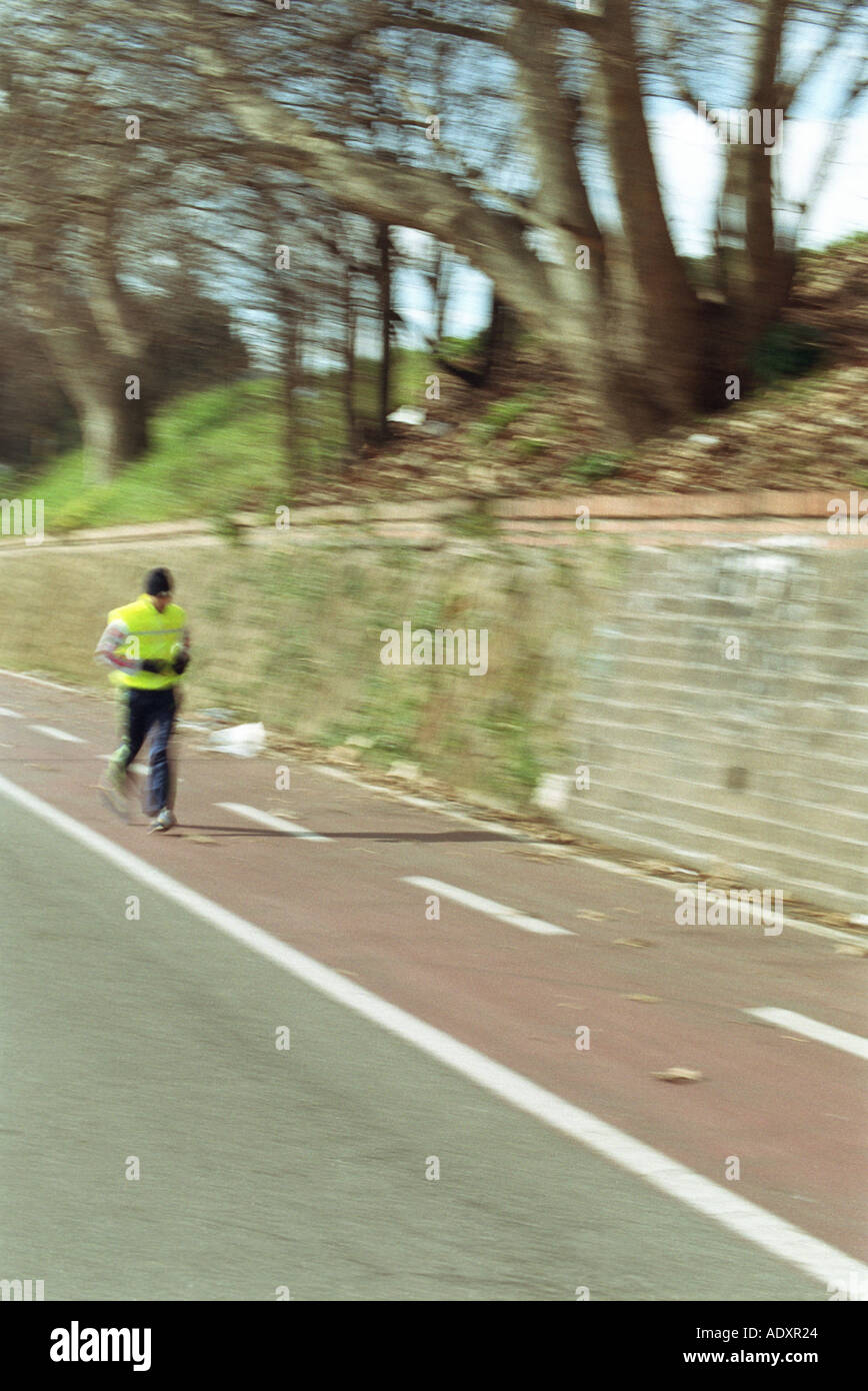 man running with yellow high visibility jacket on cycle path movement ...