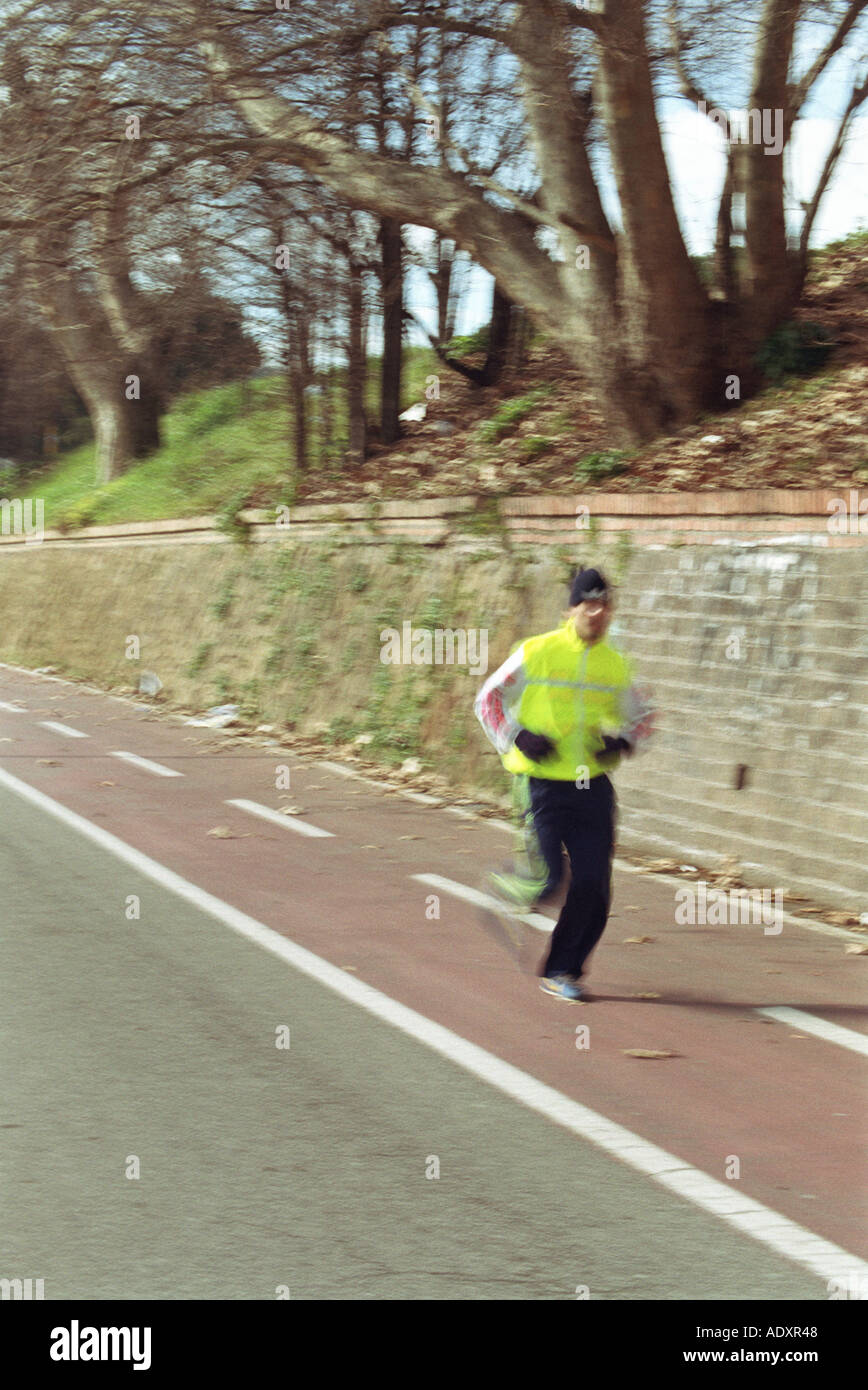man running with yellow high visibility jacket on cycle path movement ...
