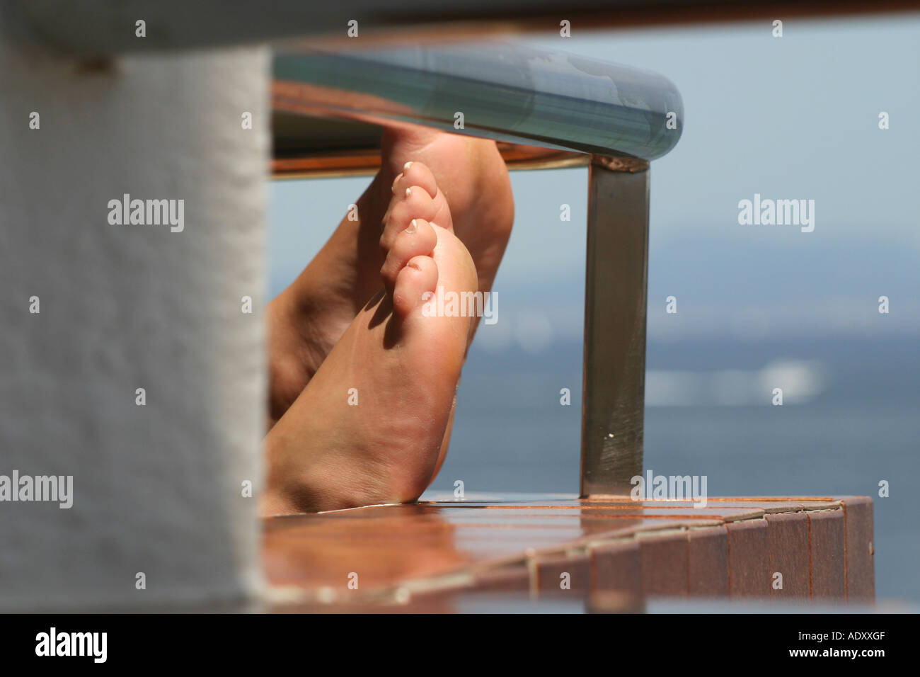 Pair of female feet resting on hotel balcony rail Stock Photo - Alamy