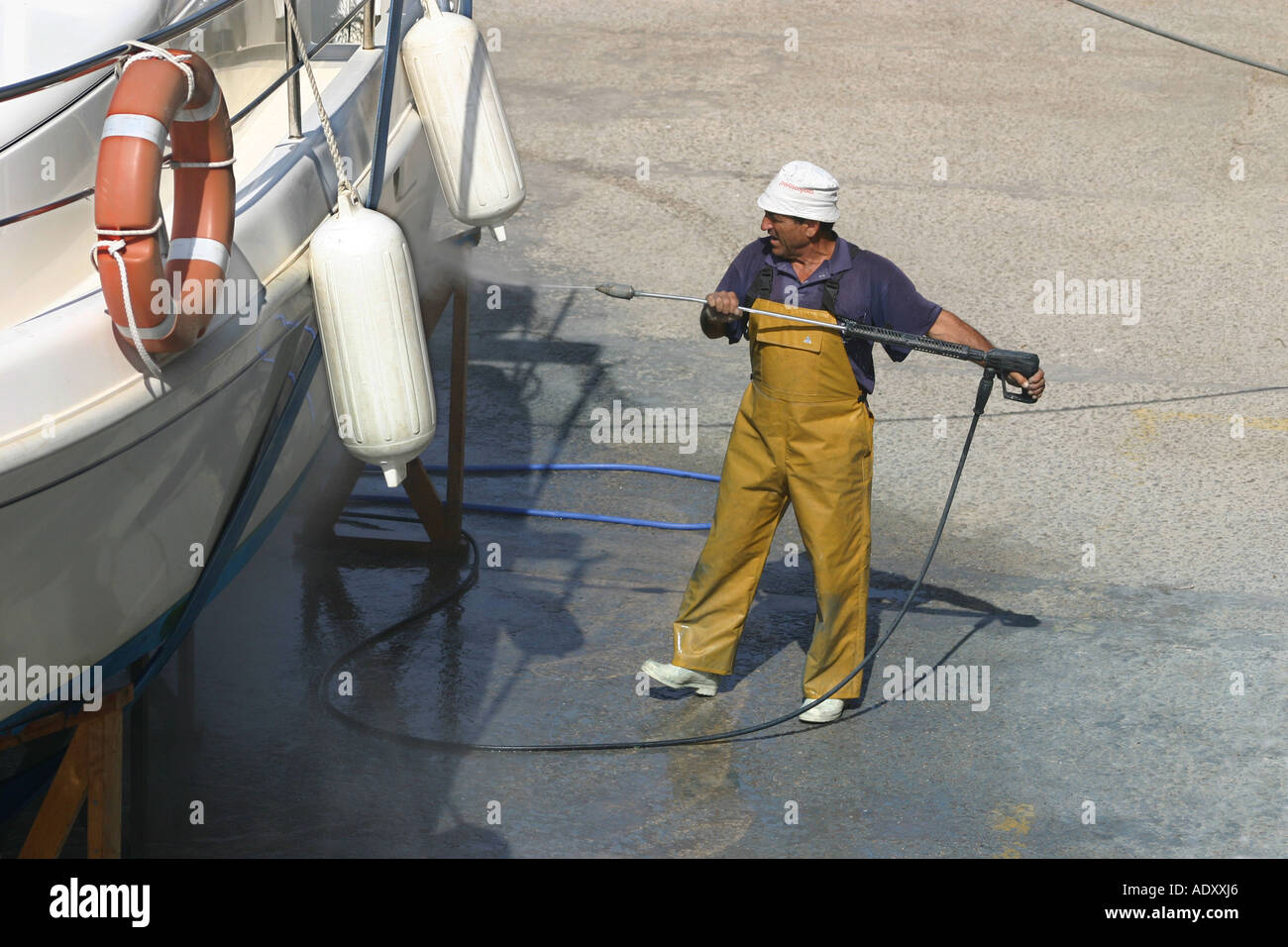 Man in waterproof safety gear using high pressure water jetting to ...