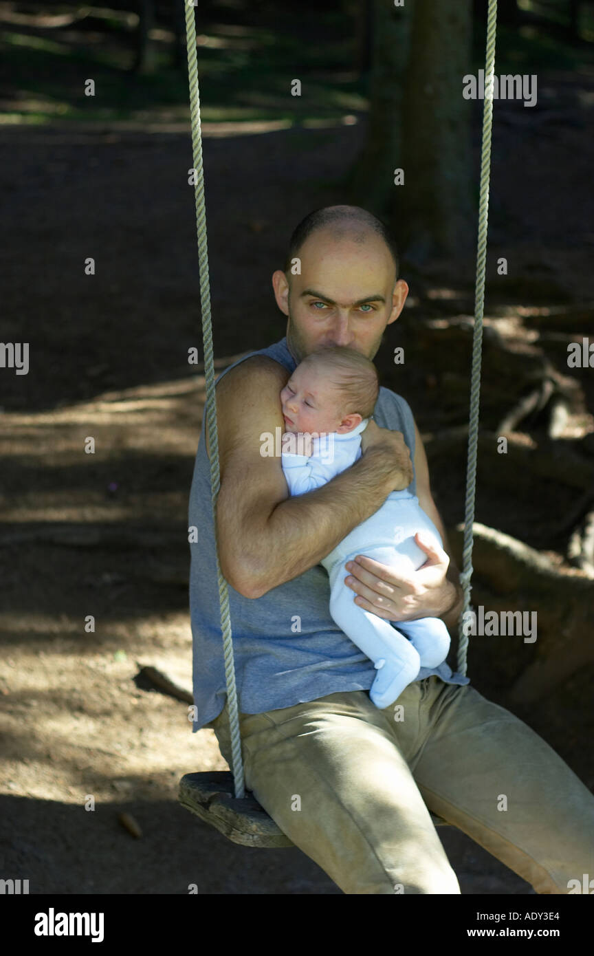 man sitting with baby on swing Stock Photo - Alamy