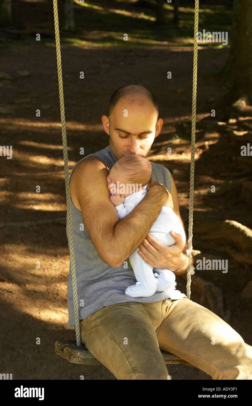 man sitting with baby on swing Stock Photo - Alamy