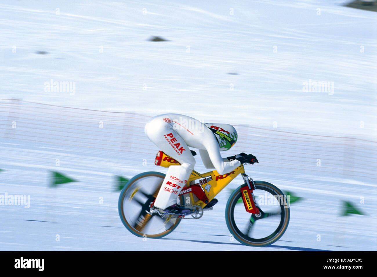 high speed snow biker, driving downhill in aerodynamic position ...