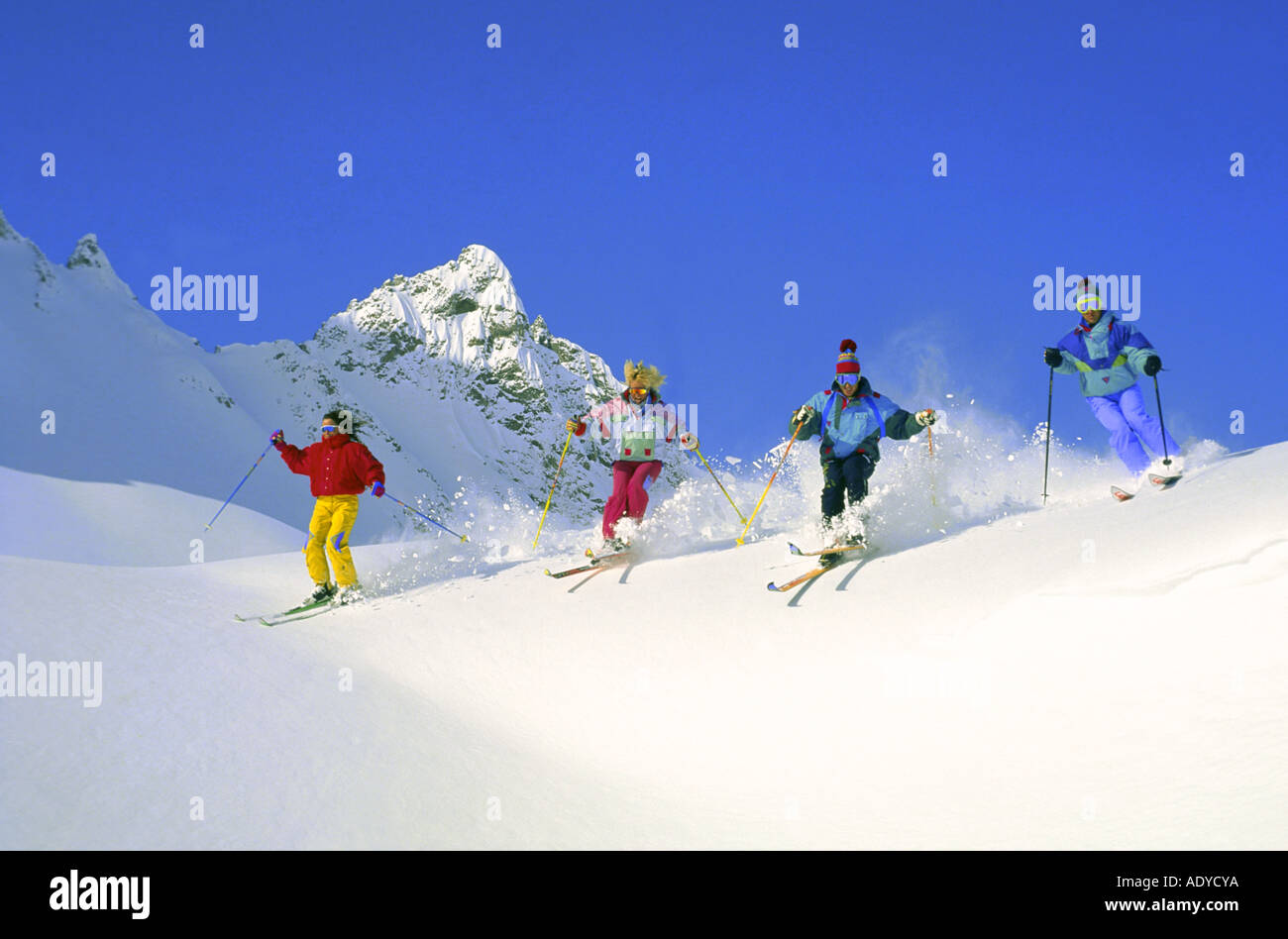 group of skier, skiing downhill side by side, with snow-capped mountain ...