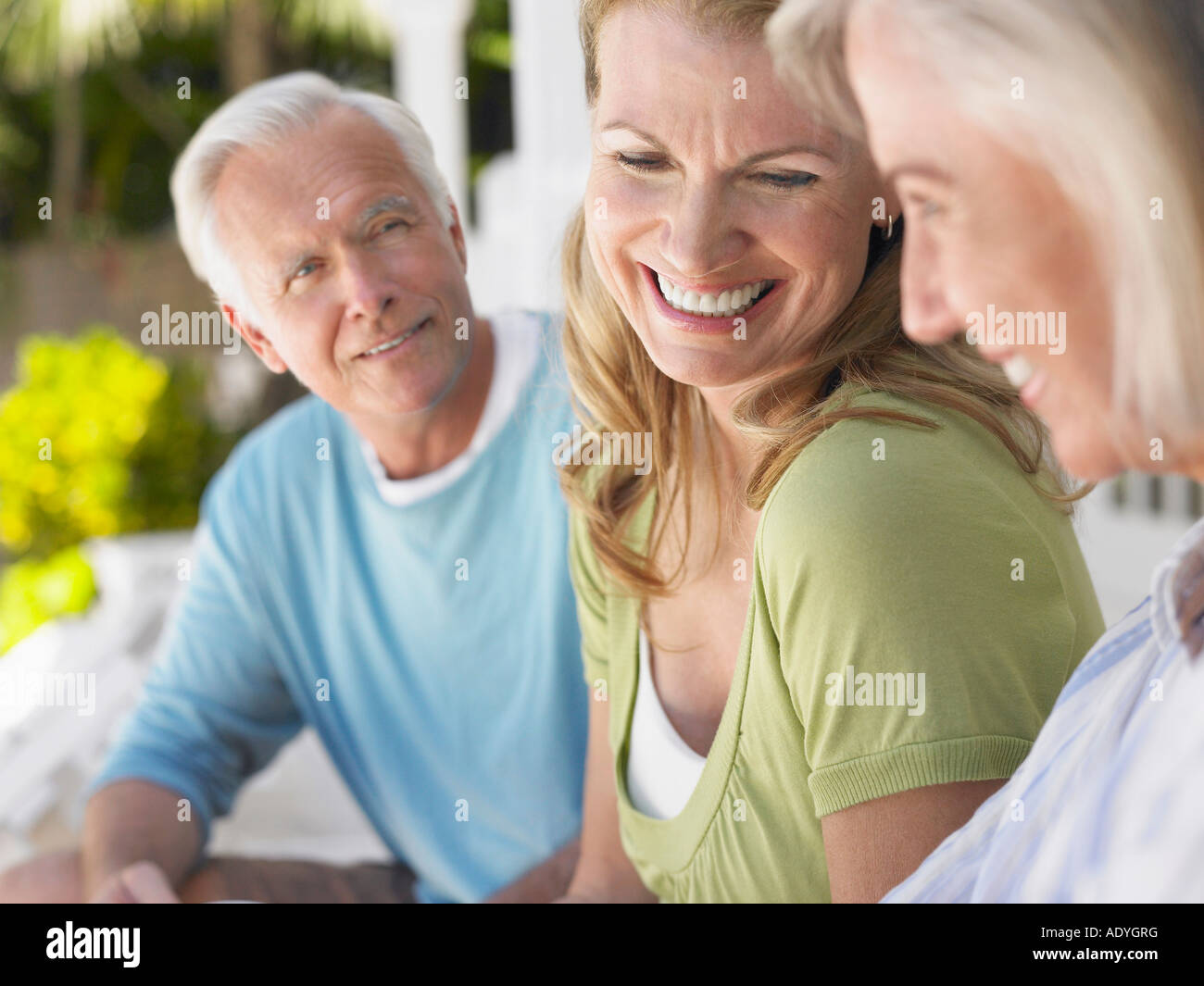 Three people sitting on verandah Stock Photo - Alamy