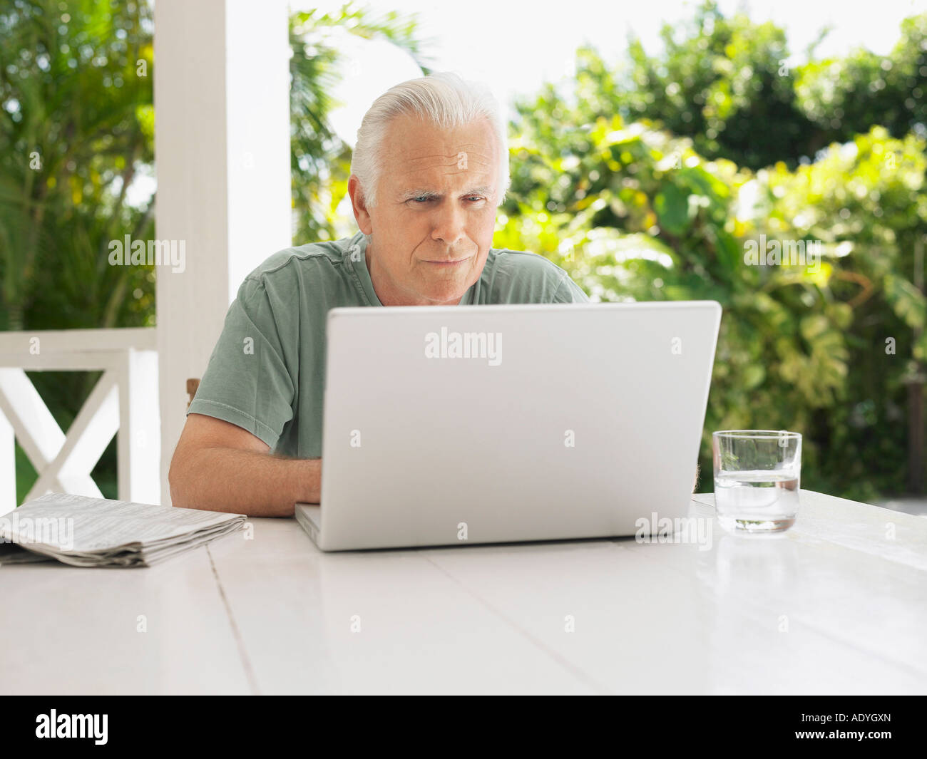 Man using laptop at verandah table Stock Photo - Alamy