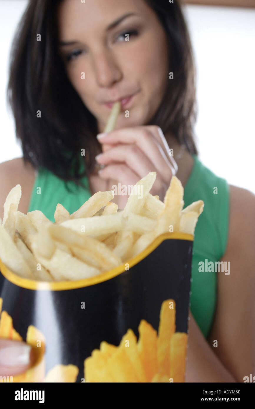young brunette woman eating French fries Stock Photo - Alamy