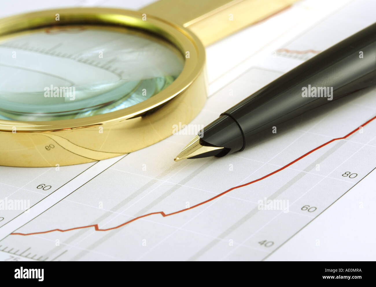 A pen and a magnifying glass on a chart Stock Photo - Alamy