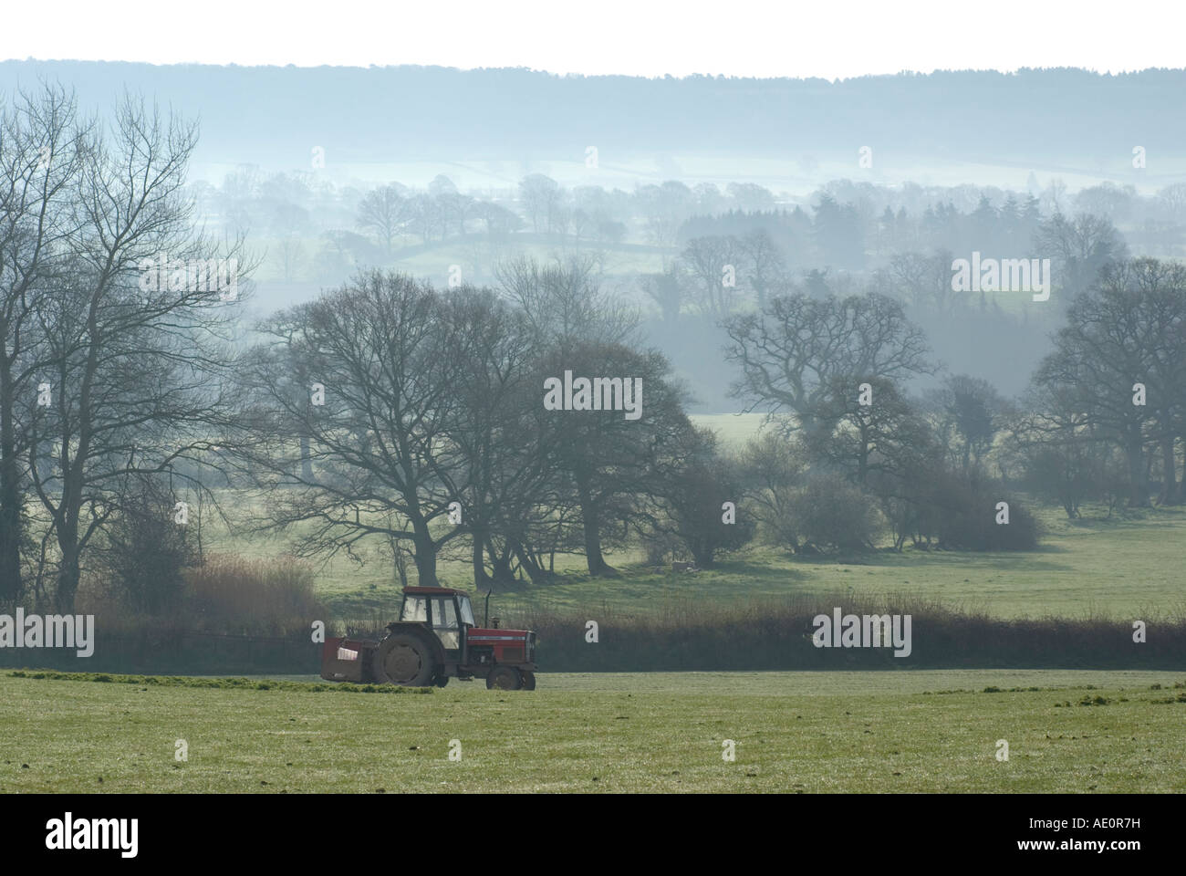 Tractor in field in morning mist Stock Photo - Alamy